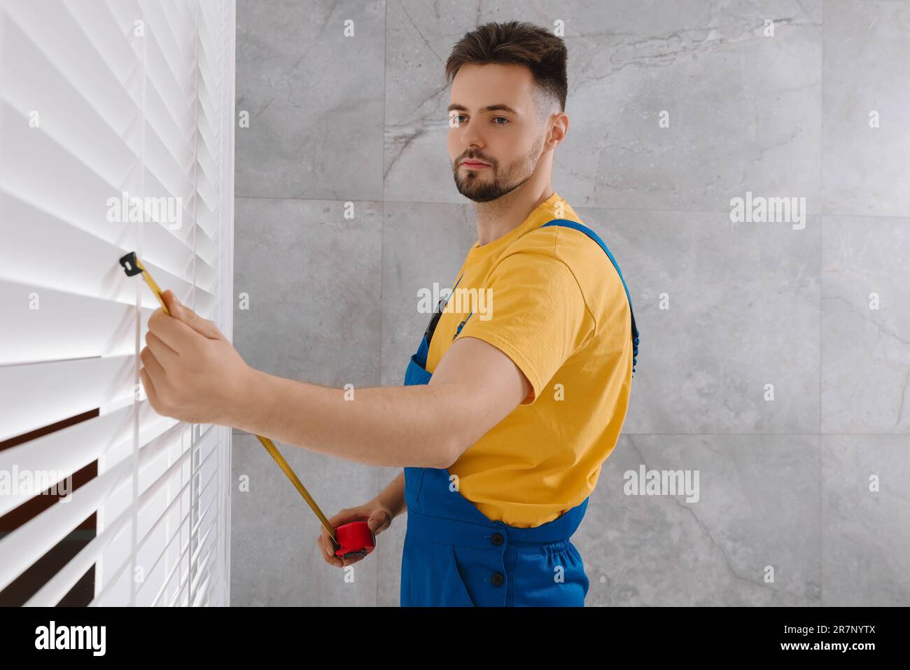 Worker in uniform using measuring tape while installing horizontal ...