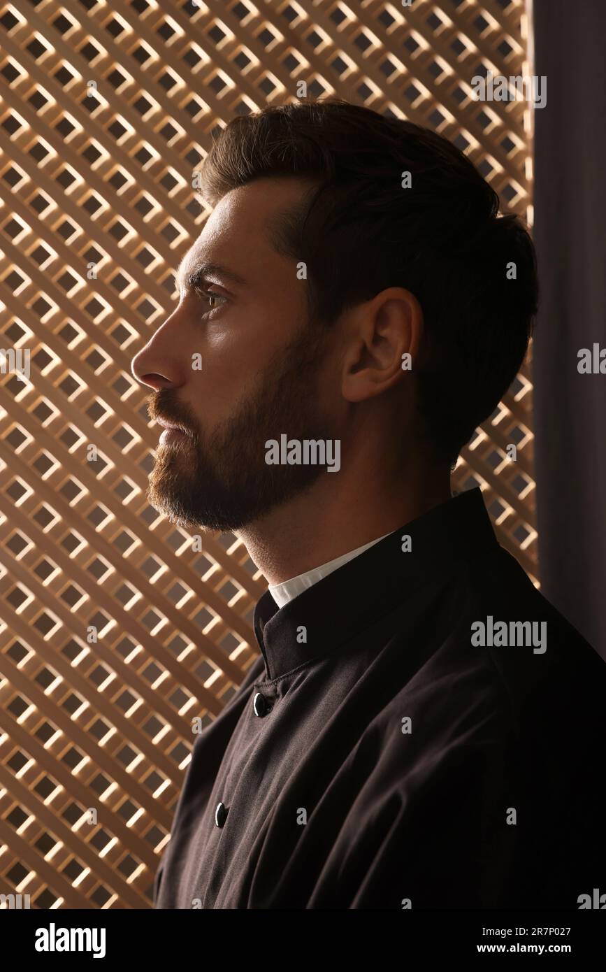 Catholic priest wearing cassock in confessional booth Stock Photo - Alamy