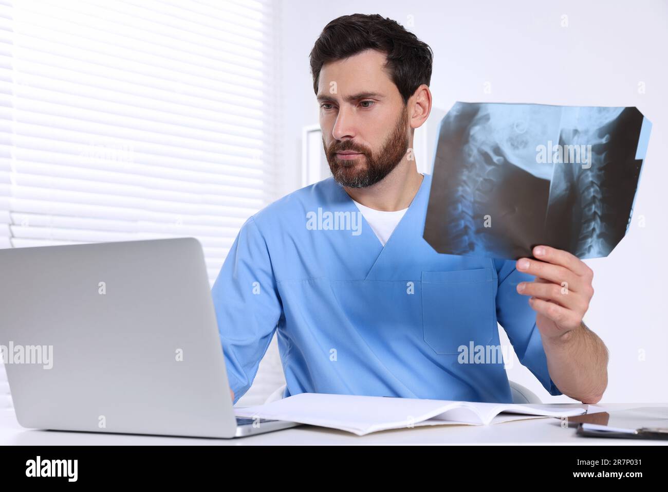 Doctor holding neck MRI scan and working on laptop in hospital Stock ...