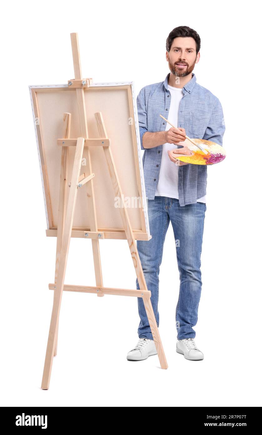 Man painting with brush against white background. Using easel to hold ...