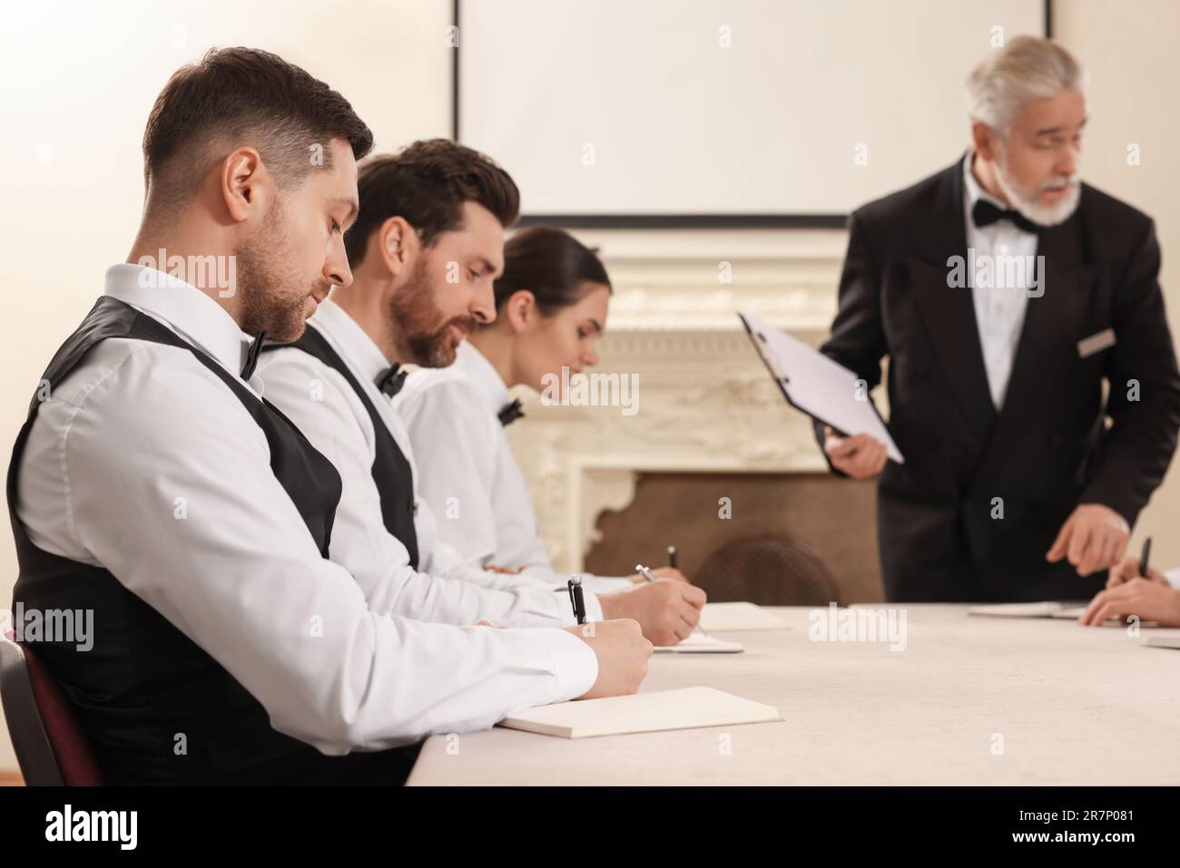 Senior man in formal suit teaching trainees indoors. Professional ...