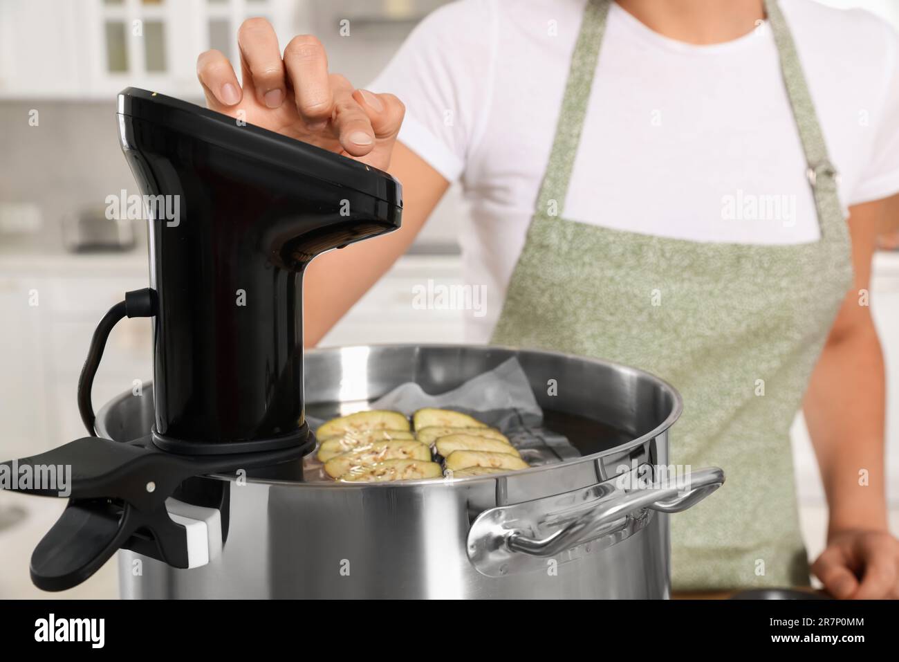 Woman using thermal immersion circulator in kitchen, closeup. Sous vide ...