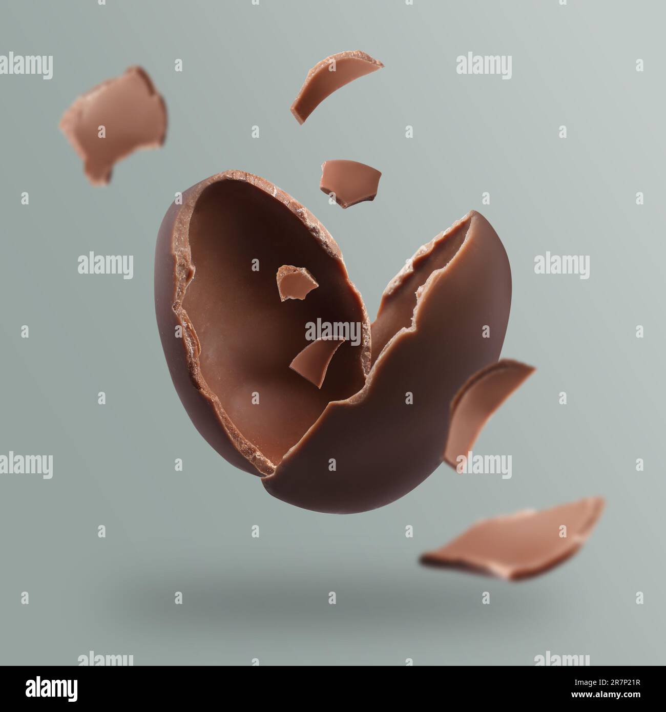 Exploded milk chocolate egg on grey background Stock Photo - Alamy
