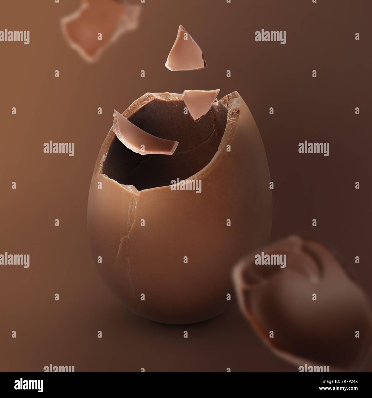 Exploded milk chocolate egg on brown background Stock Photo - Alamy