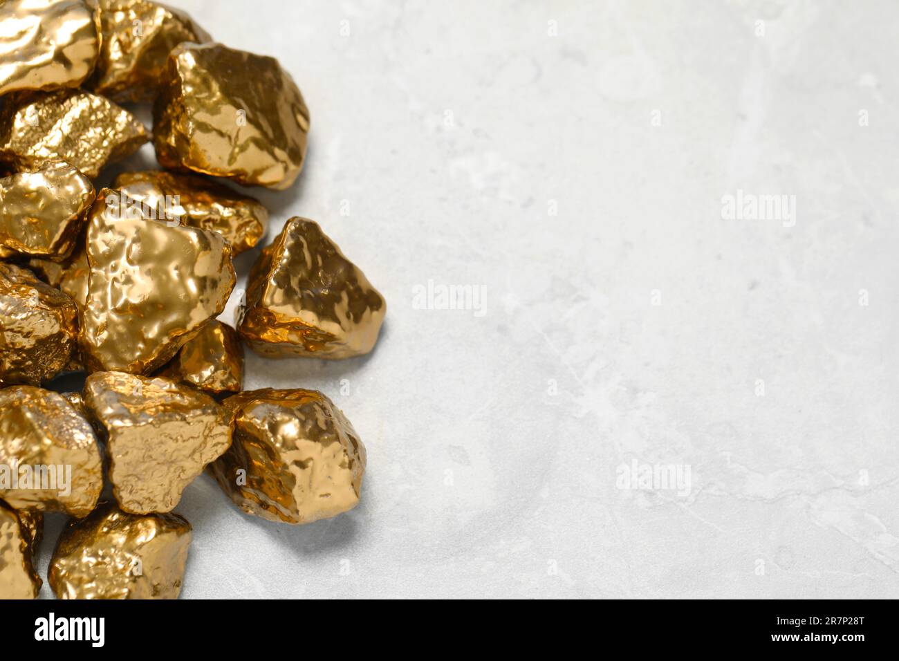 Pile of gold nuggets on light grey marble table, flat lay. Space for ...