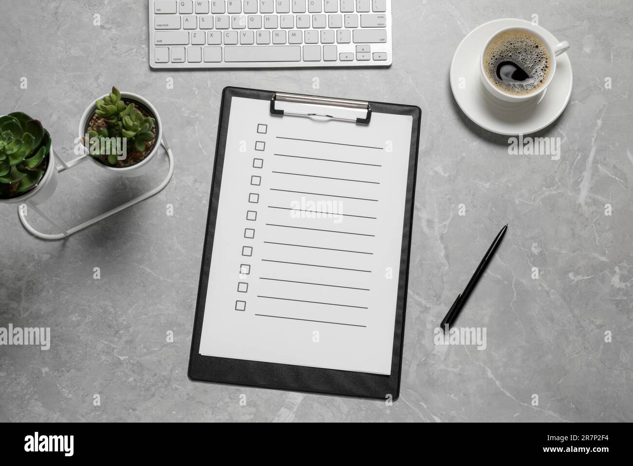 Clipboard with checkboxes, cup of coffee, plants and computer keyboard ...