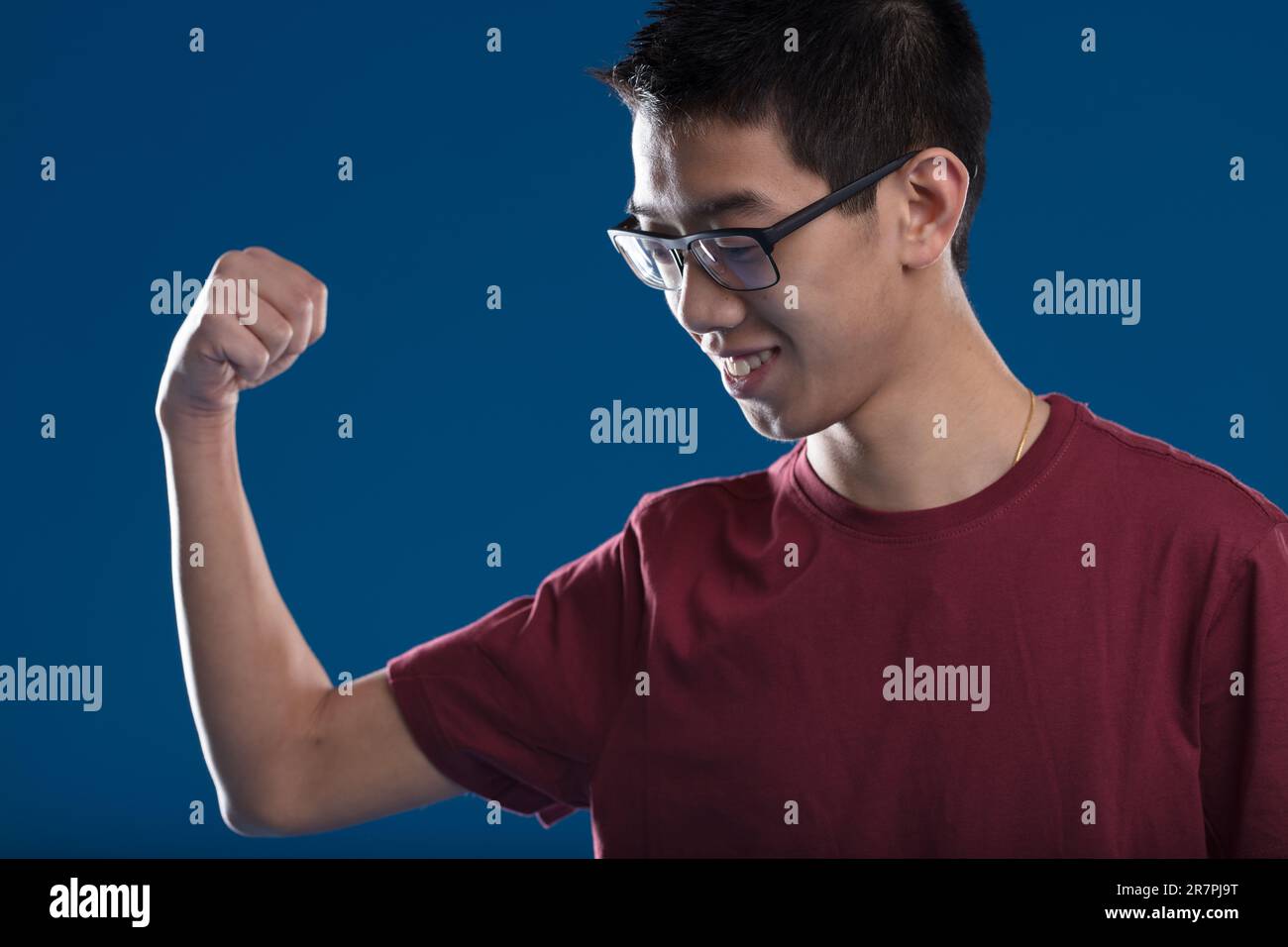 An East Asian man, with glasses, expresses joy by raising his arm ...