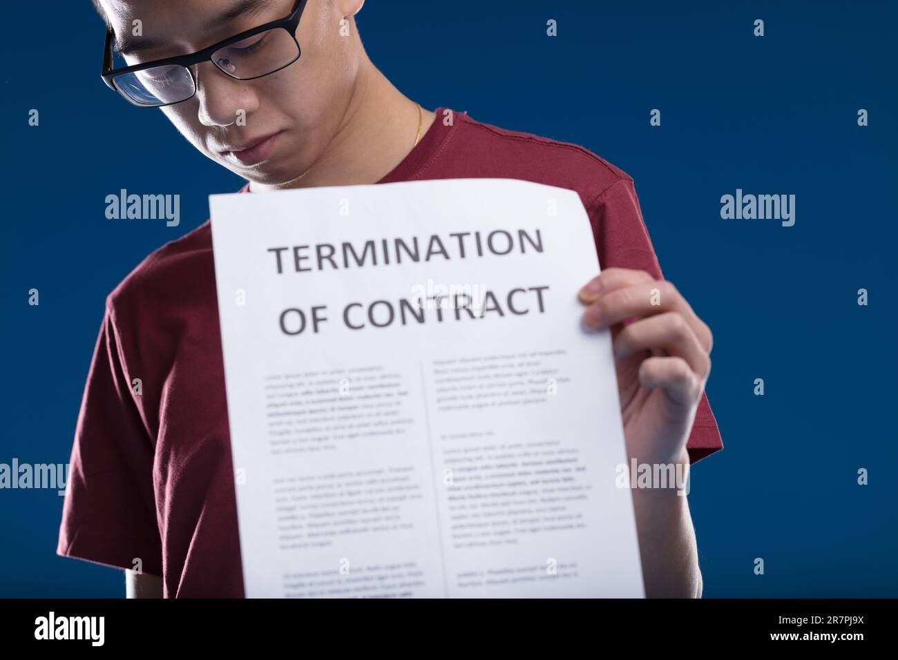 Young man of East Asian descent holds a blurred termination letter ...