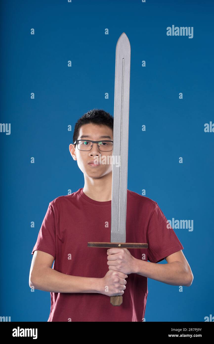 A young, casually dressed employee, East Asian, wields a symbolic sword ...