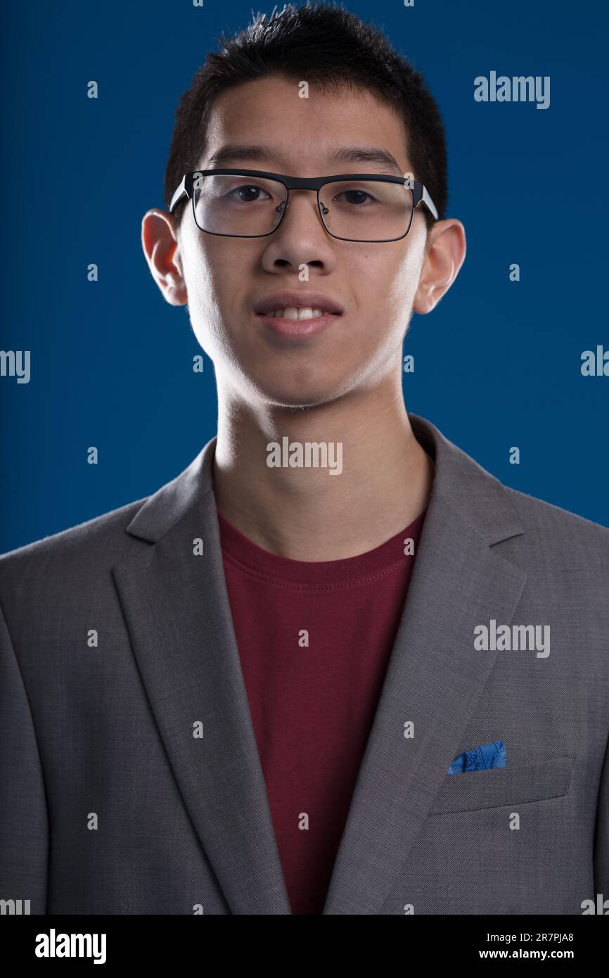Happy Asian man in a grey jacket over a burgundy shirt and black ...
