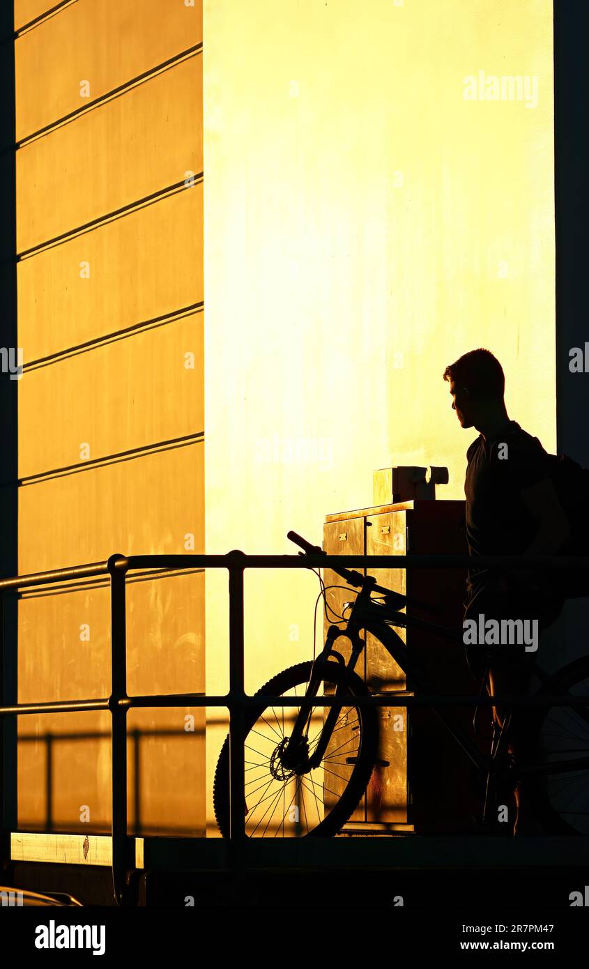 Random street photography, of a person's silhouette with a bike at dusk ...