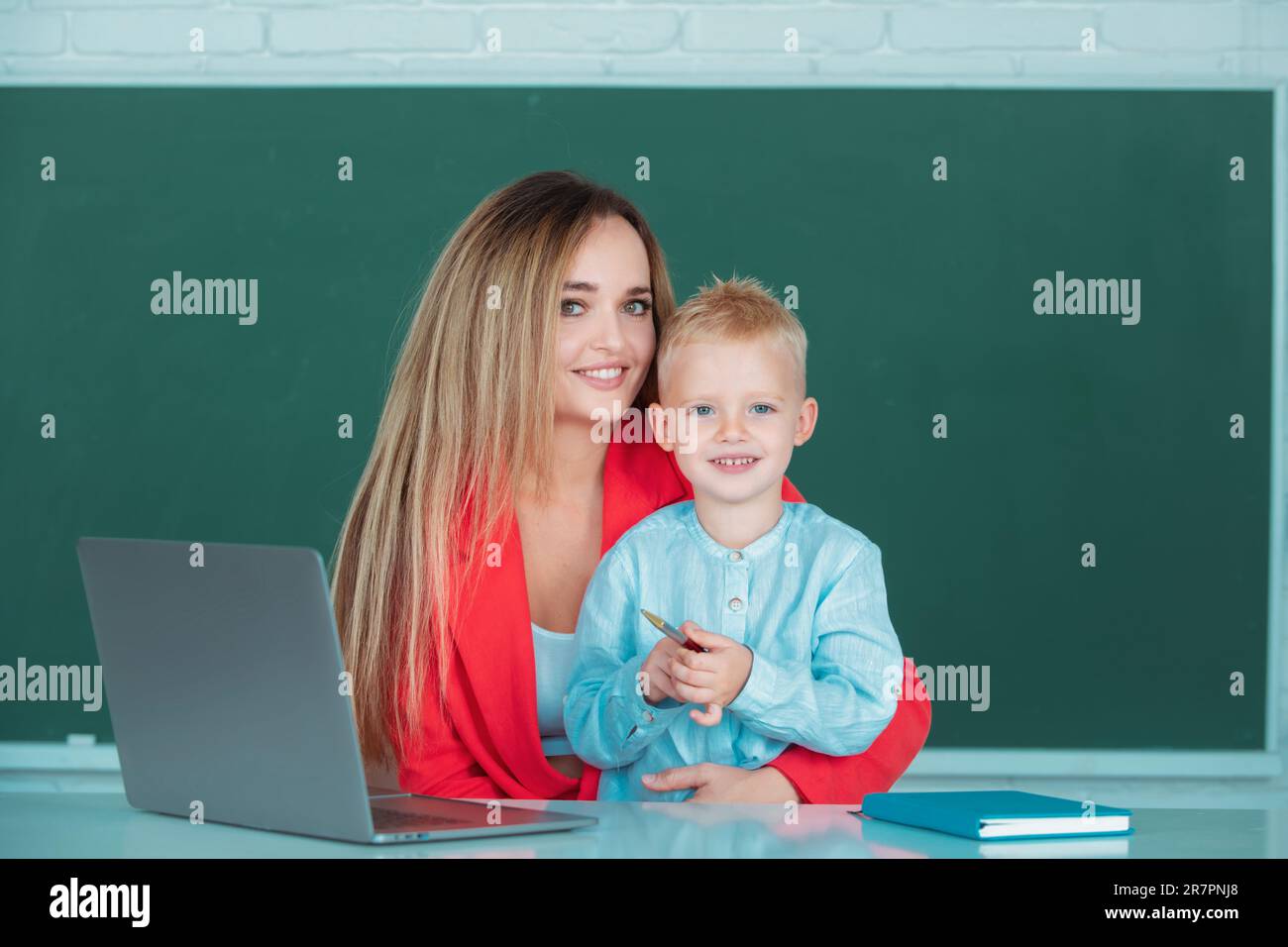 Elementary school teacher and pupil in classroom. Mother and son ...