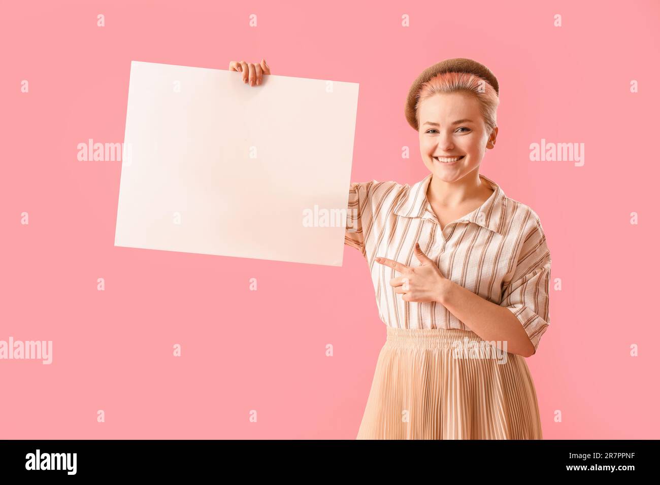 Young woman pointing at blank poster on pink background Stock Photo - Alamy