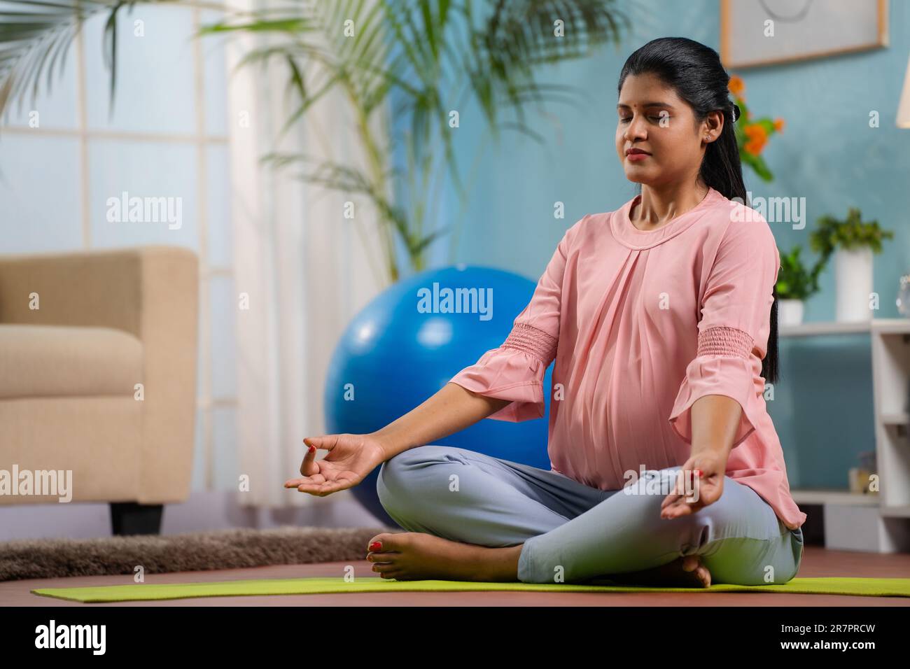 Indian peaceful pregnant woman in lotus pose doing meditation on yoga ...