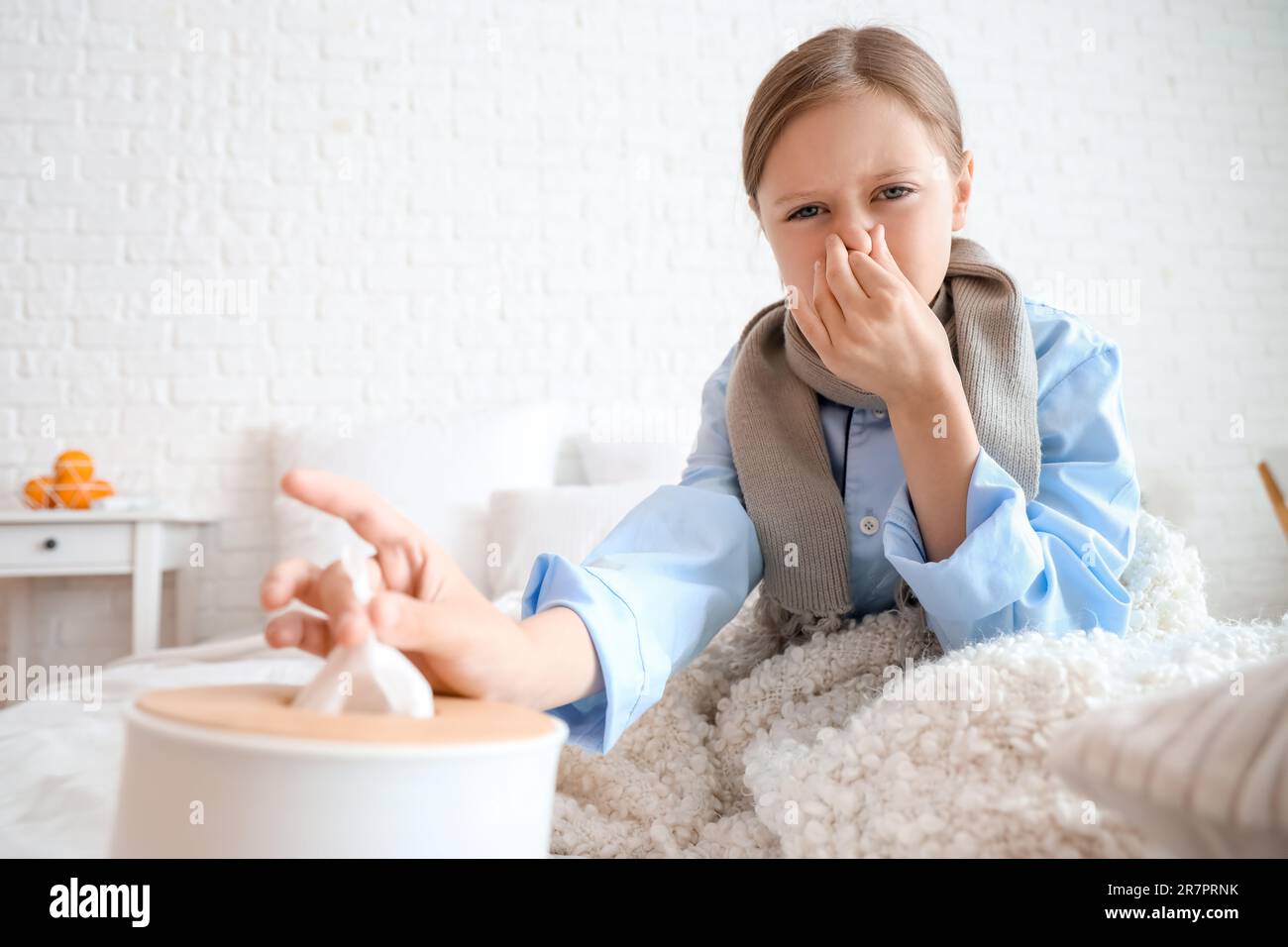 Ill little girl with runny nose taking tissue in bedroom Stock Photo ...