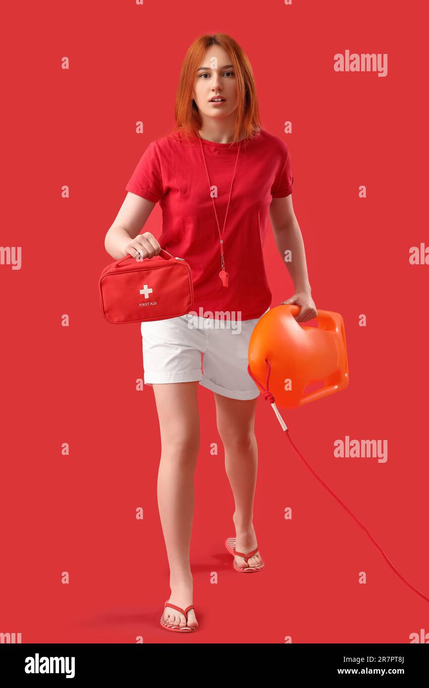Female lifeguard with rescue buoy and first aid kit on red background ...