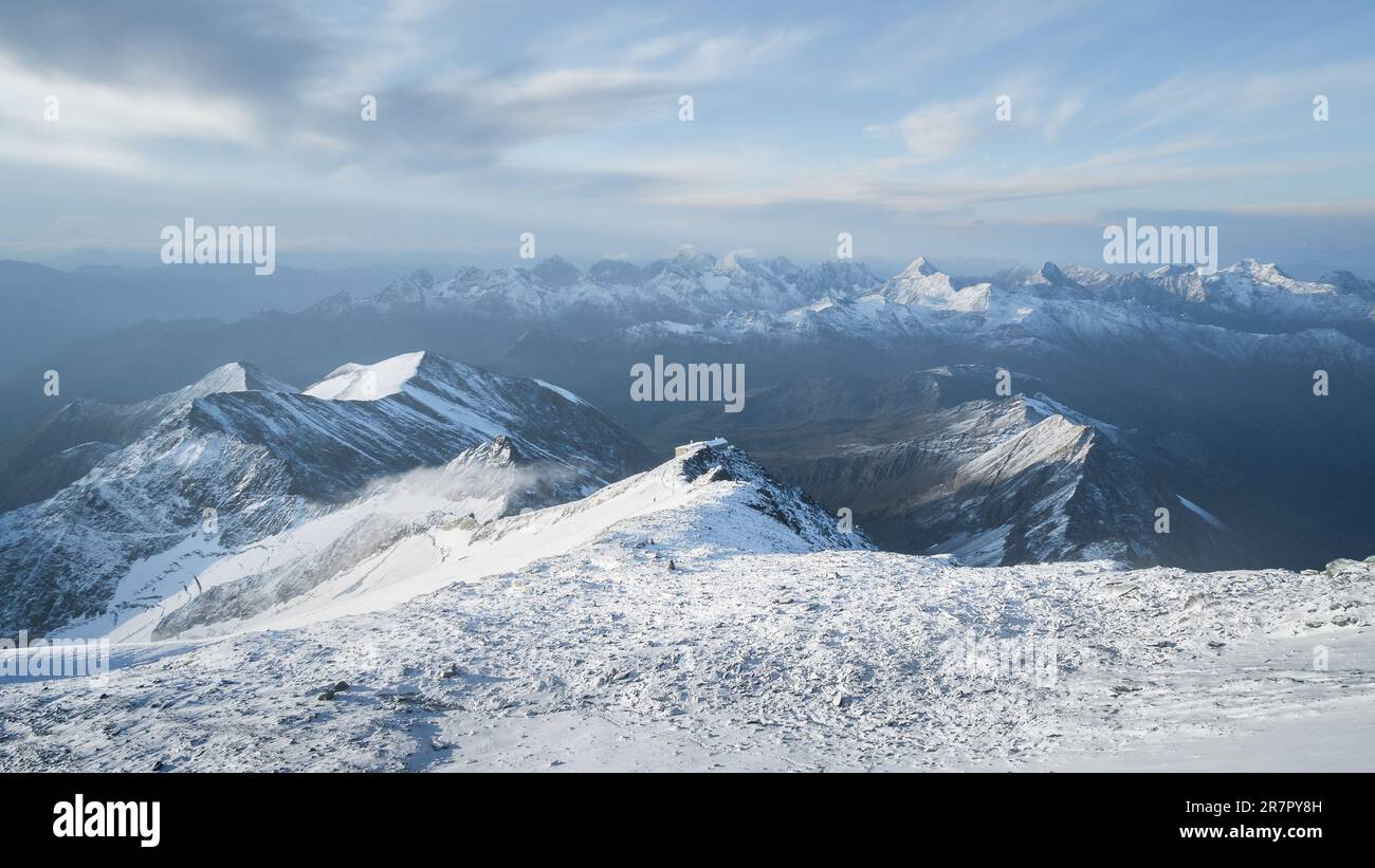 Alpine landscape with hut surrounded by big peaks covered by snow and ...