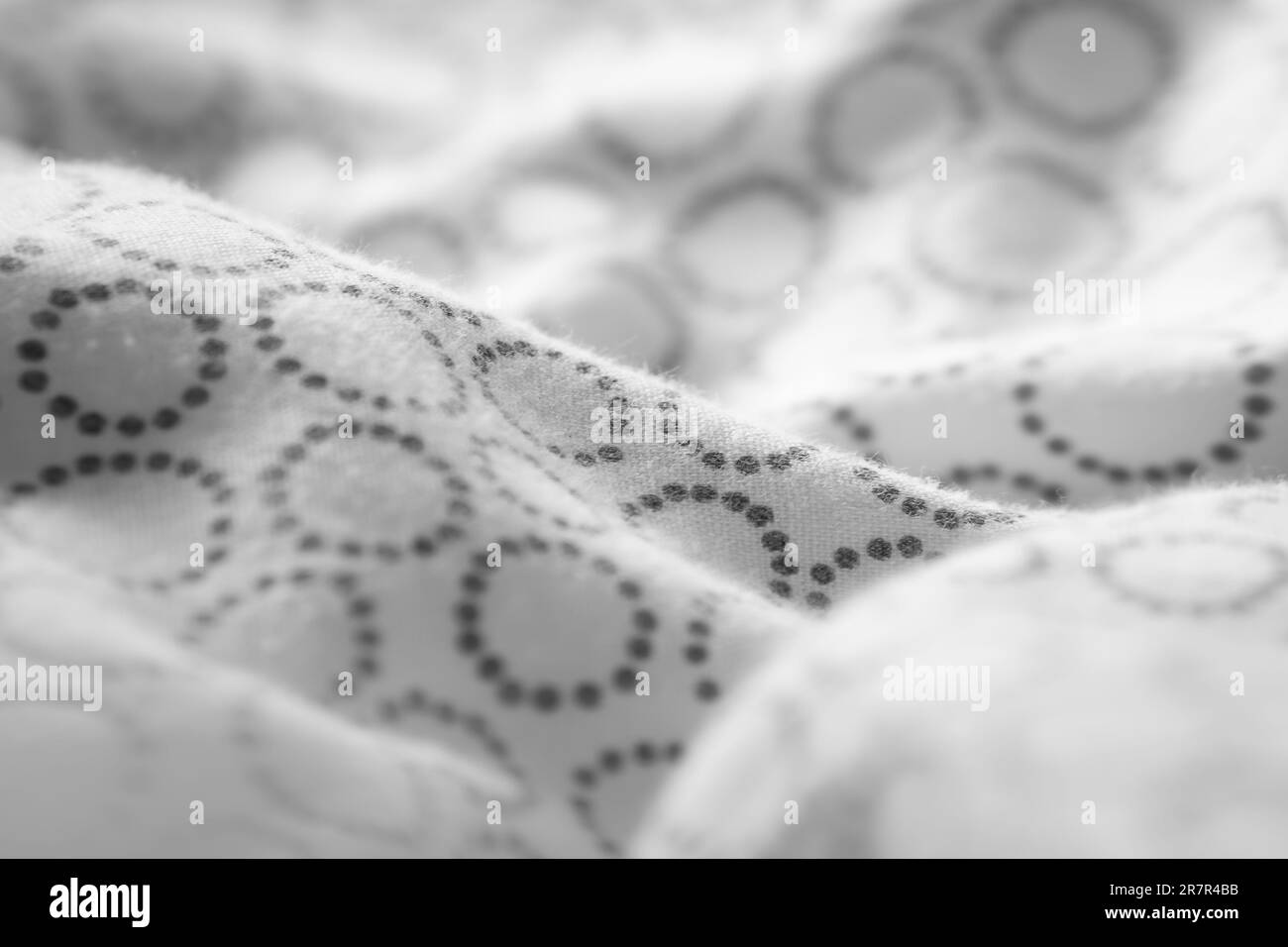 close up of fold, wrinkled, crumbled white duvet fabric with grey dots ...