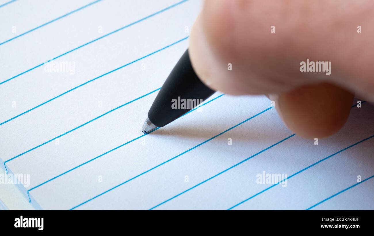 close up of hand writing with black pen on blank white paper with blue ...
