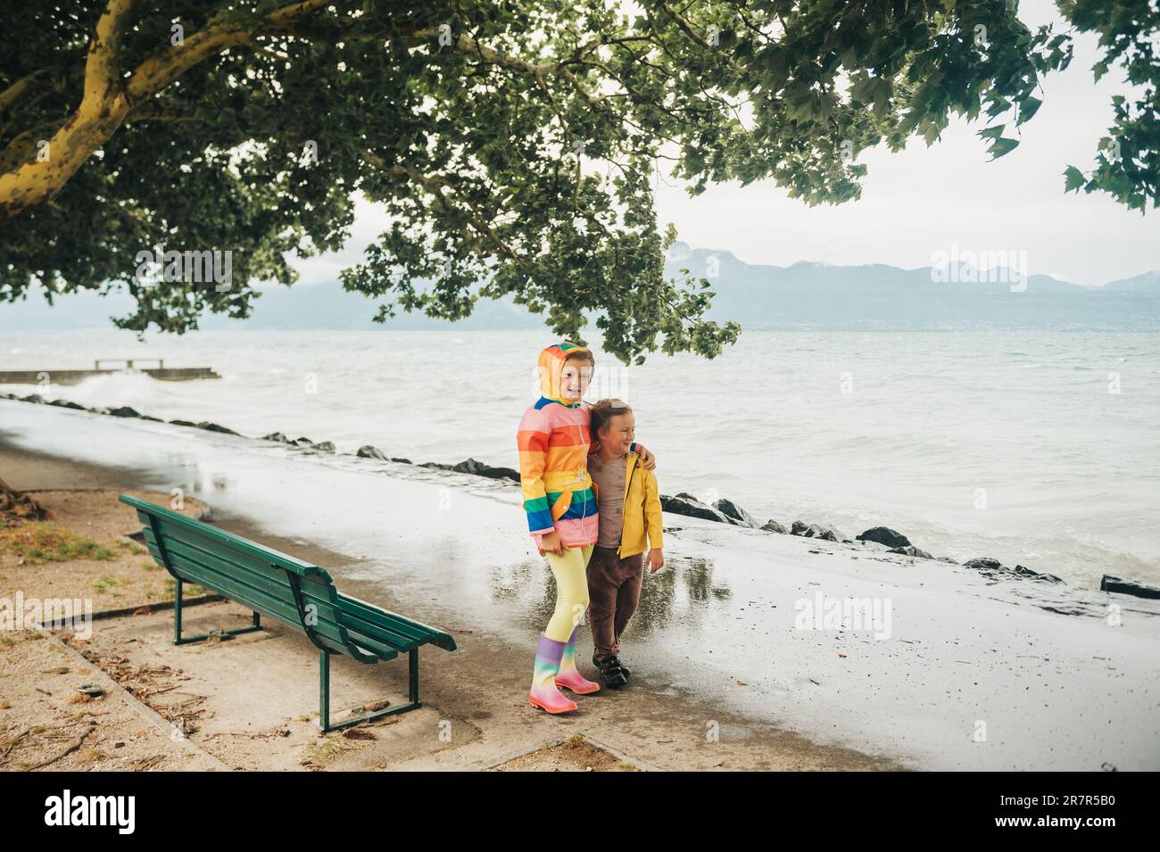 Group of two funny kids playing by the lake on a very windy day ...