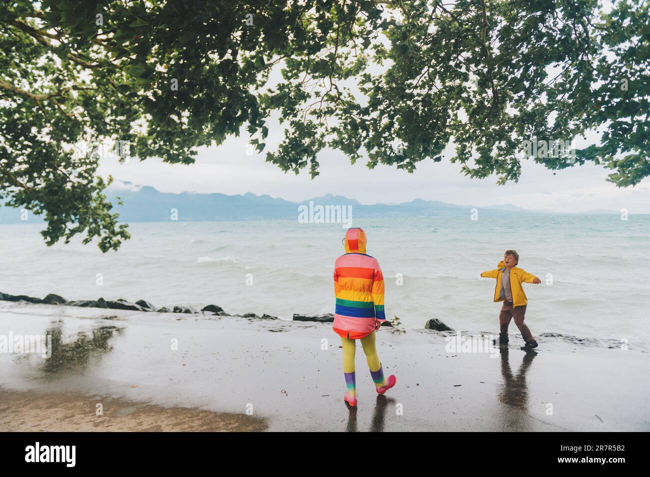 Group of two funny kids playing by the lake on a very windy day ...