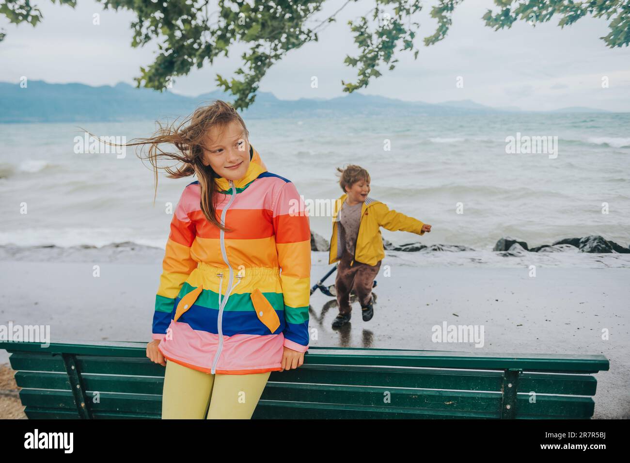 Group of two funny kids playing by the lake on a very windy day ...