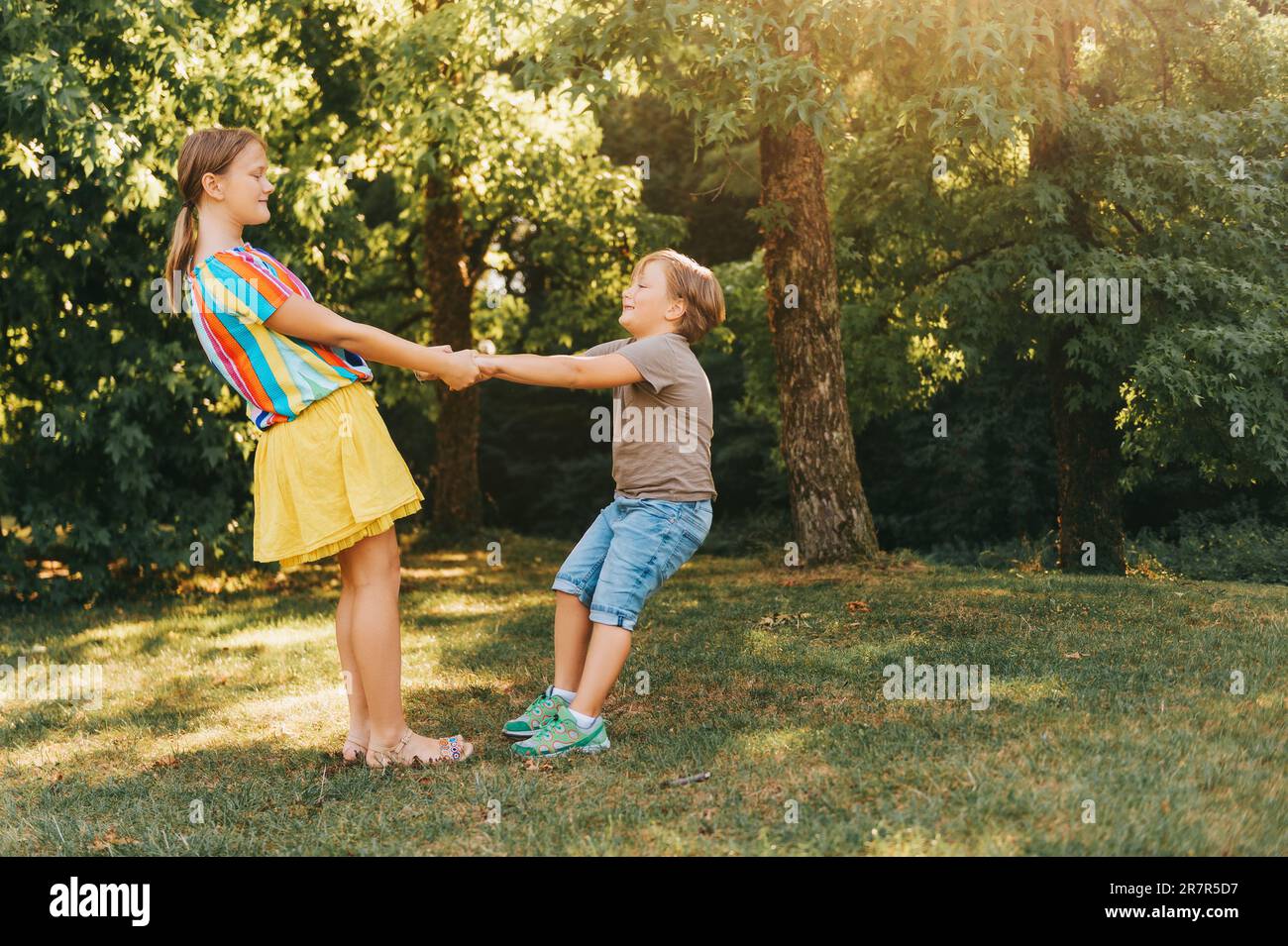 Group of two children playing together in summer park, holding hands ...