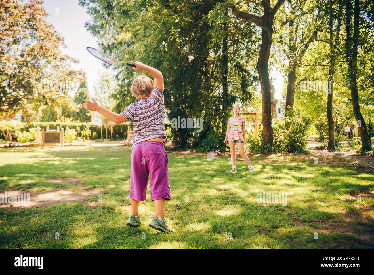 Group of 2 funny kids friends playing badminton in summer park ...