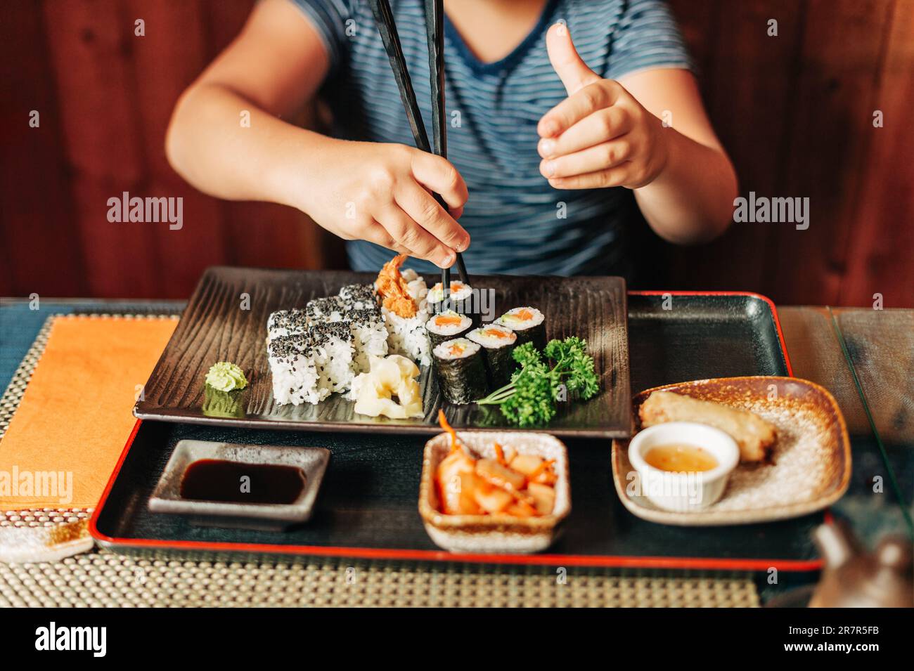 Cute kid boy eating sushi in asian restaurant Stock Photo - Alamy