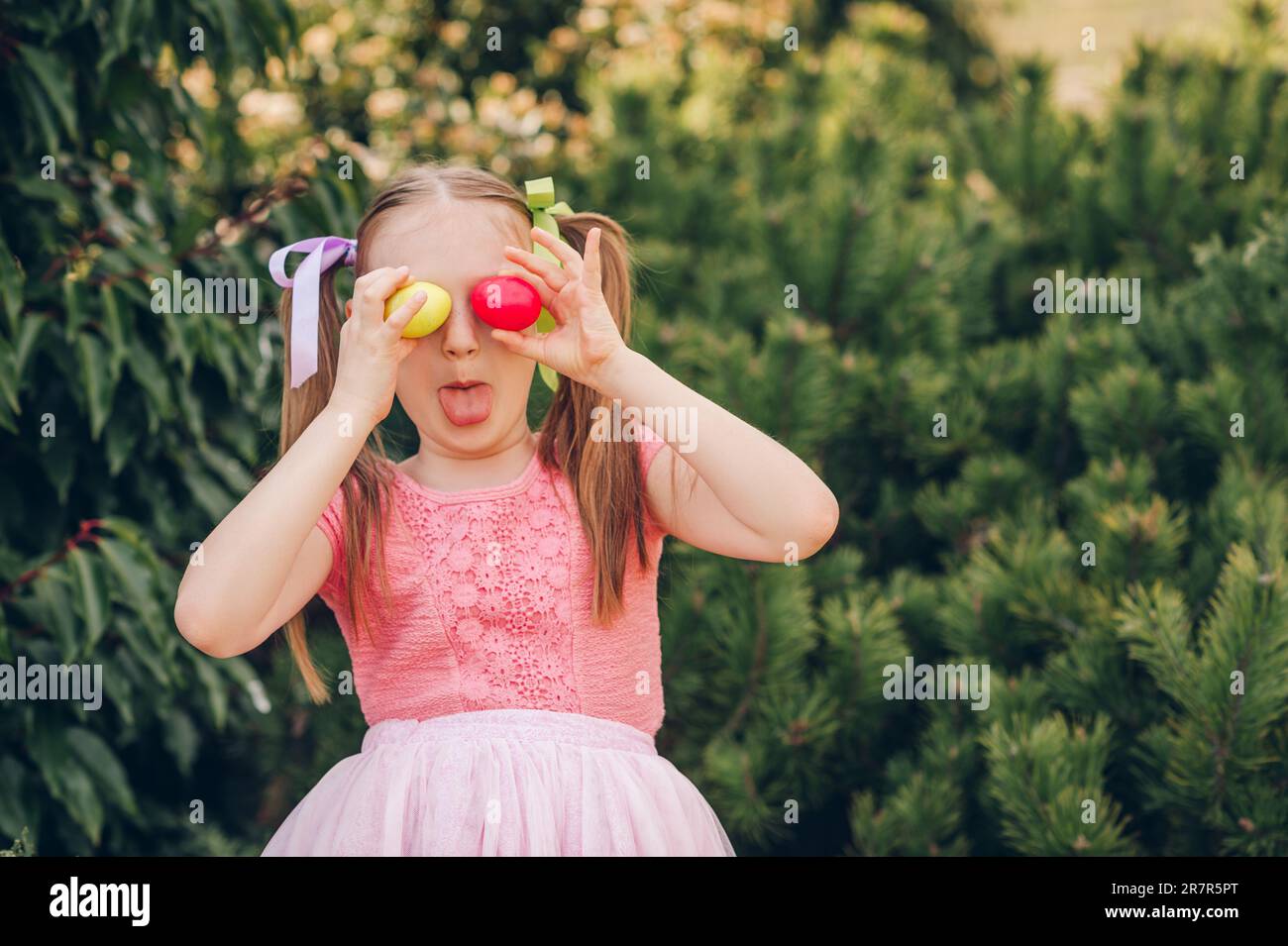 Funny kid girl pulling a tongue, holding easter eggs next to face Stock ...