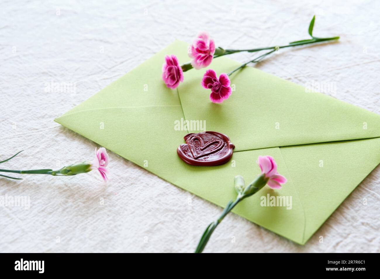 Envelope wax seal with carnation flowers on white table Stock Photo - Alamy