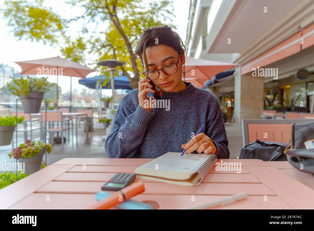 A young female is writing in a notebook while seated at a table in a ...