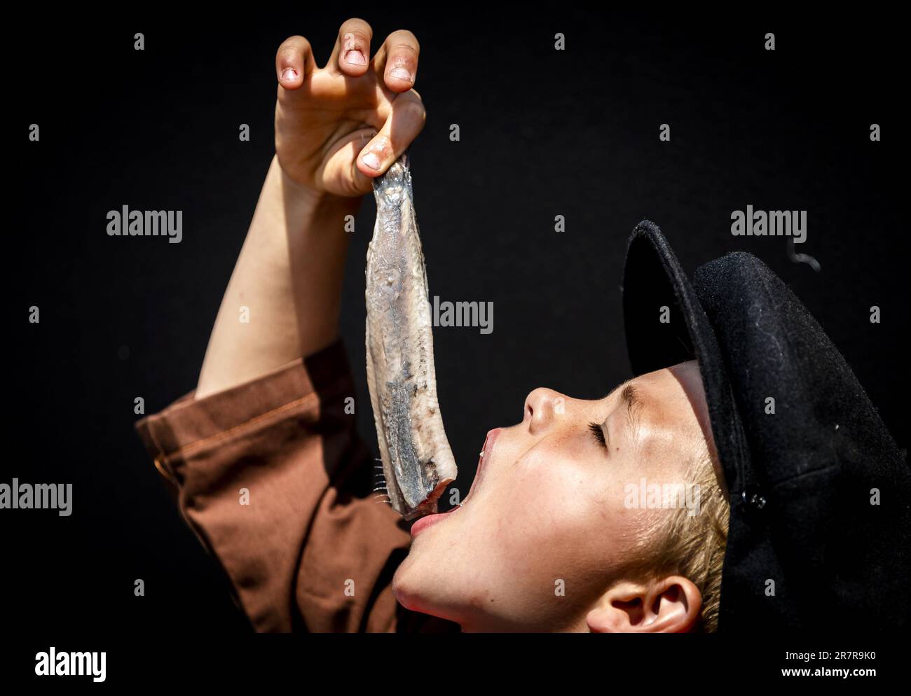 SCHEVENINGEN - A boy in traditional costume bites a herring during ...