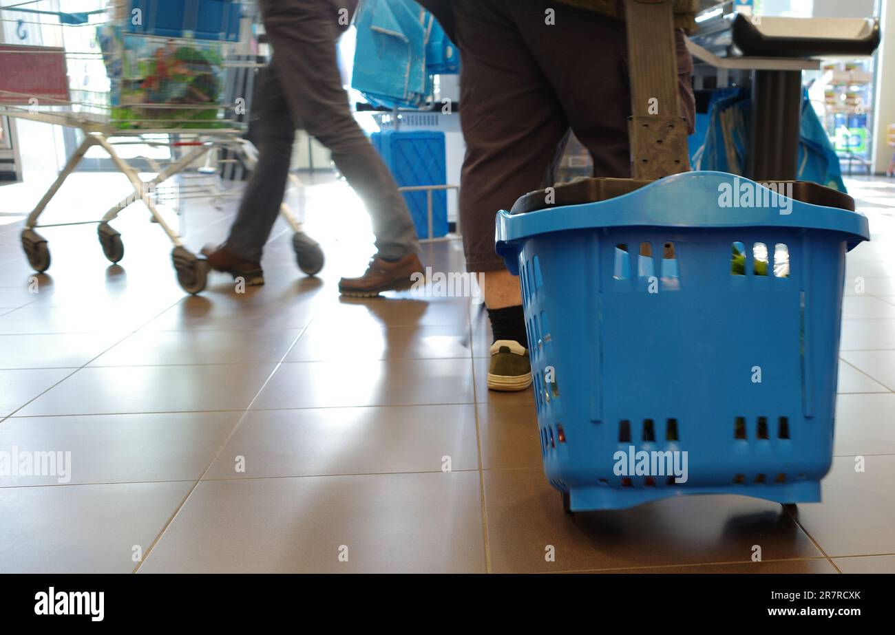 The legs of a man who is shopping. He pulls a blue plastic shopping ...