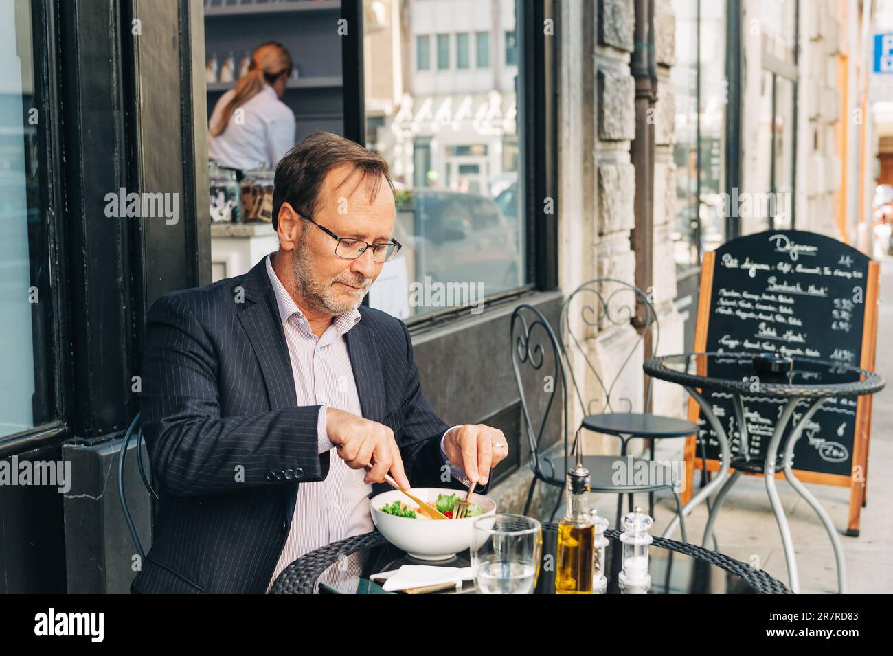 Businessman having lunch on a terrace in outdoor cafe, wearing a suit ...