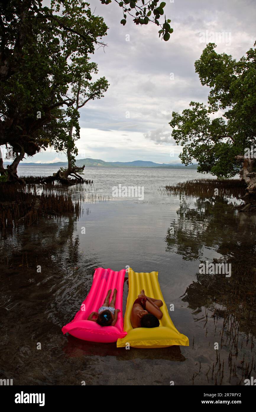 Two children, a brother and a sister, relaxing on their inflatable ...