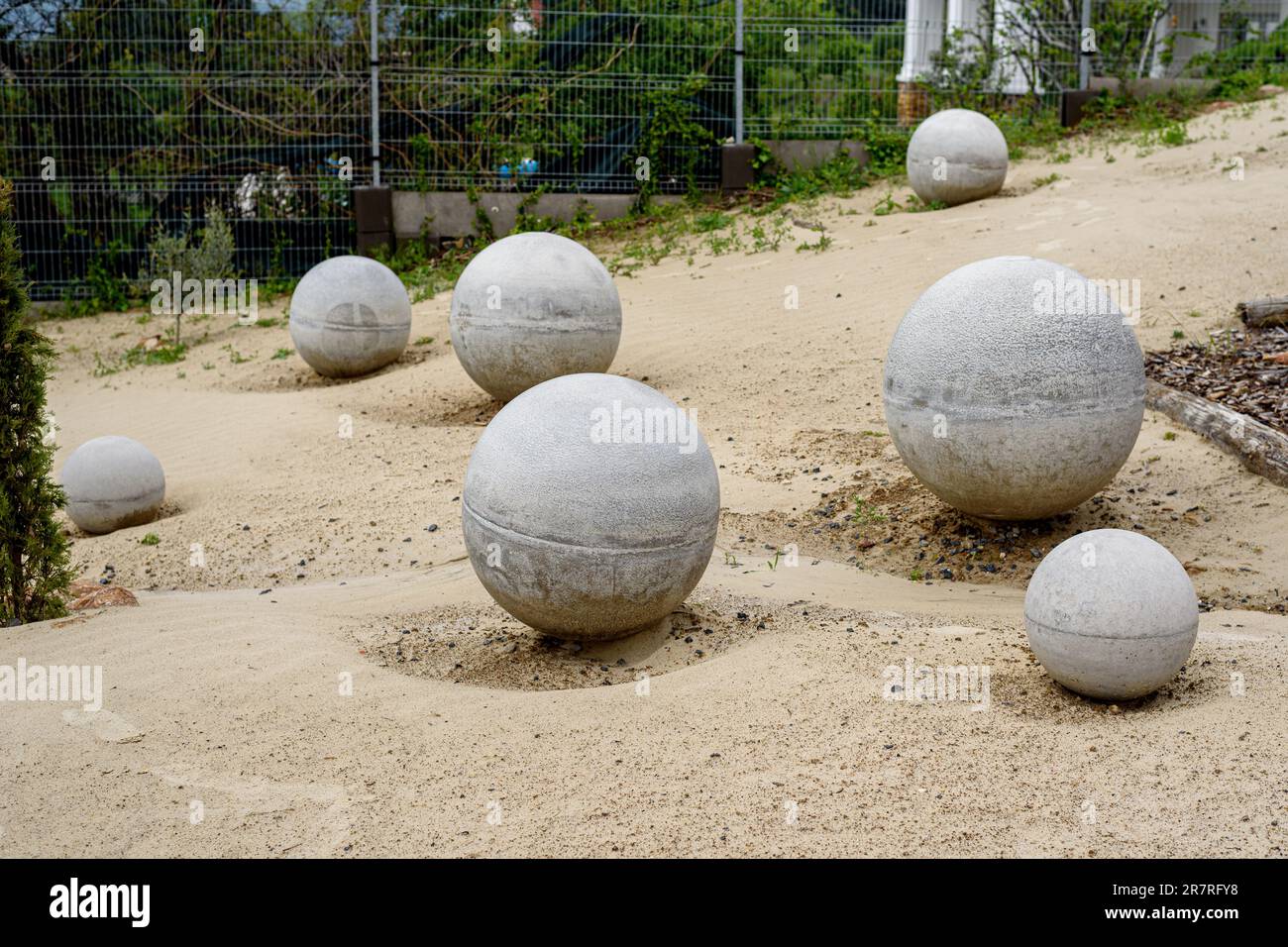 Seven concrete round spheres on sand in a garden Stock Photo - Alamy