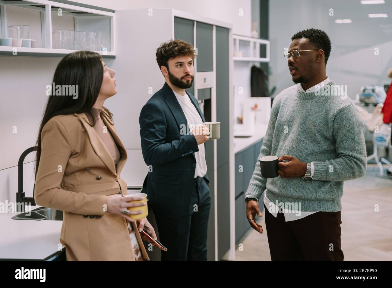 Two male and one female multiracial coworkers having a conversation at ...