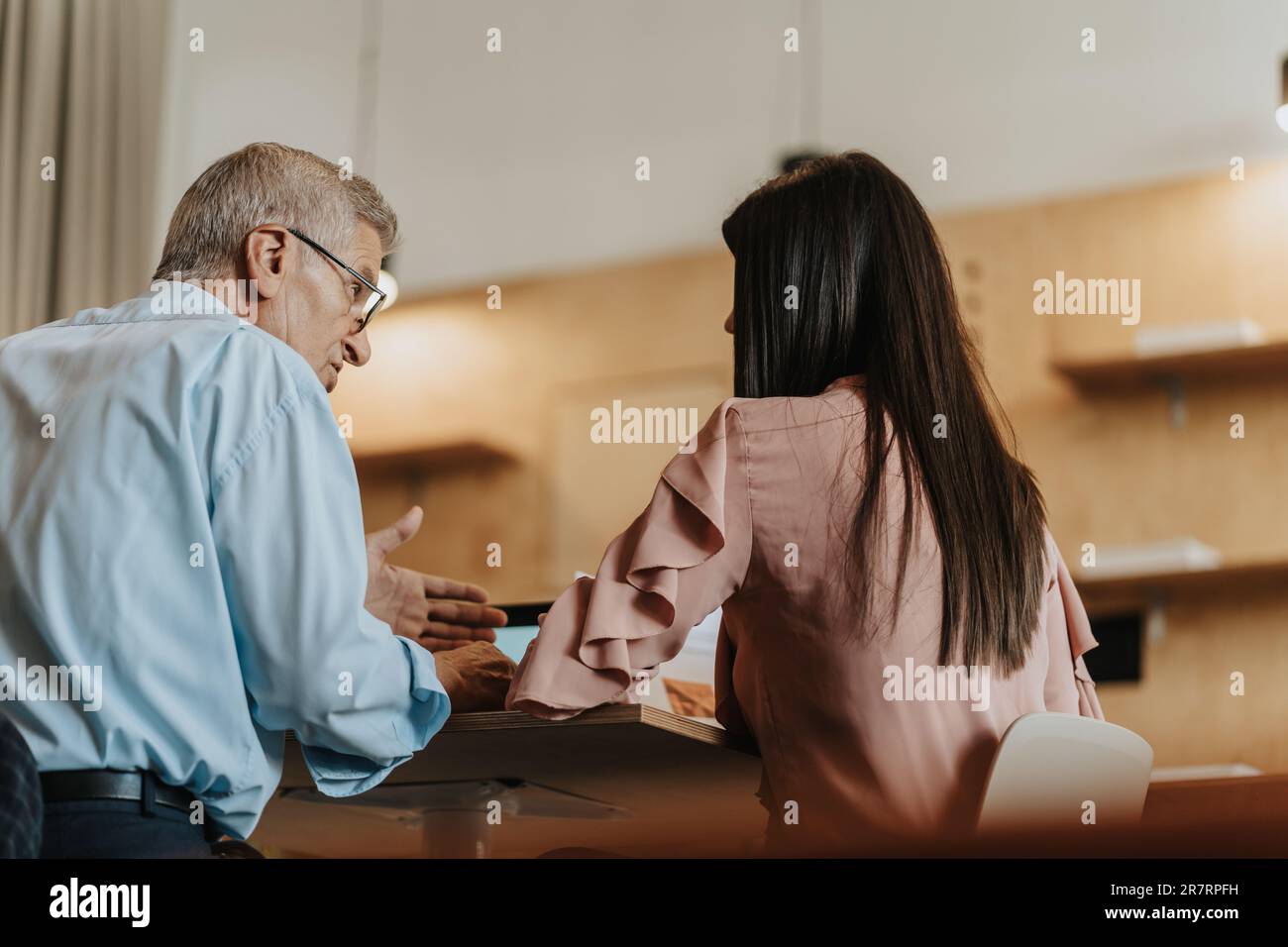 A back view shot of 70s experienced male business person giving advices ...