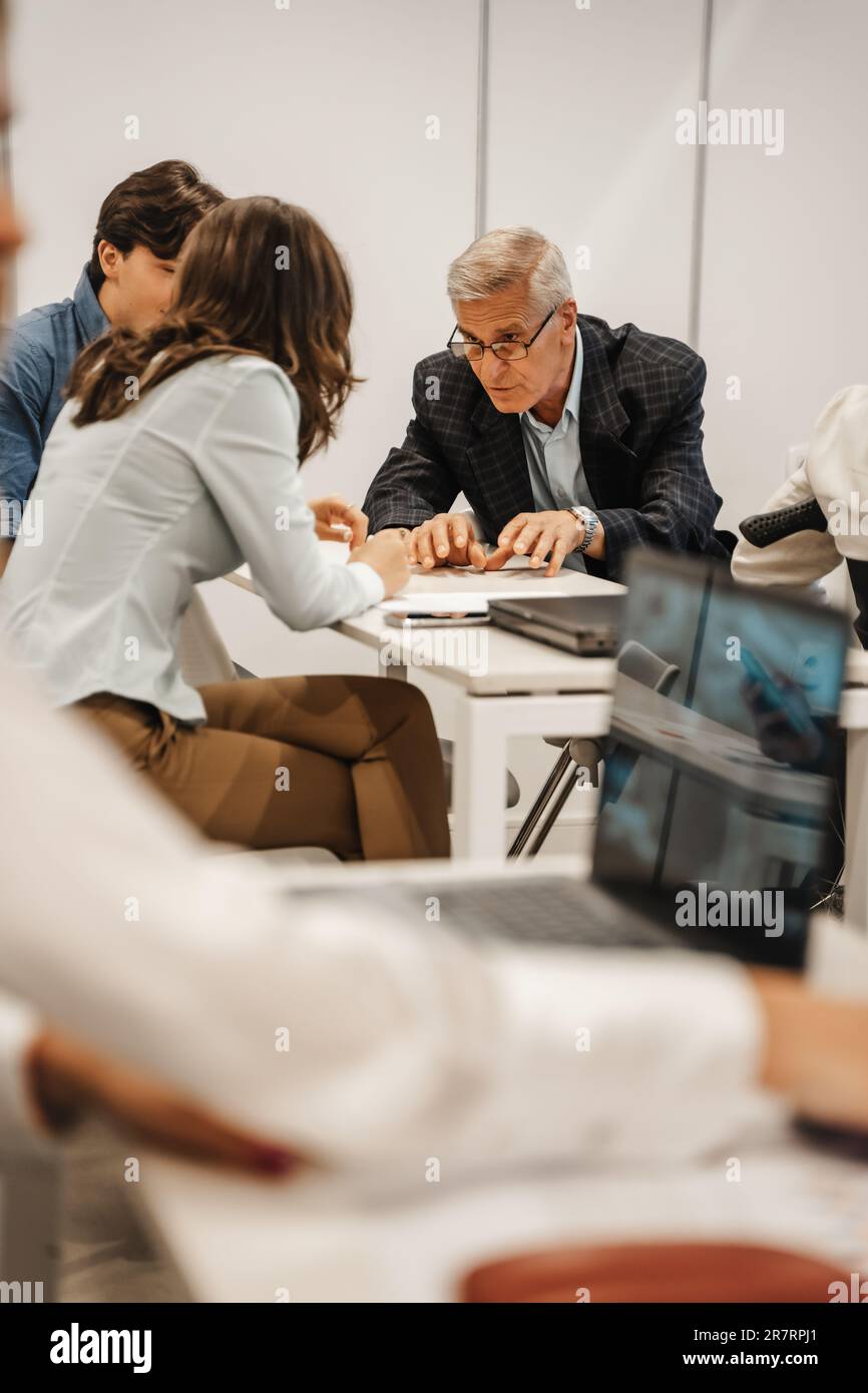 Older businessman giving tips and tricks to his young colleagues for ...