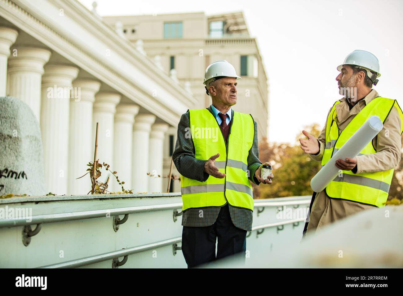 Two senior construction managers are standing and having a conversation ...