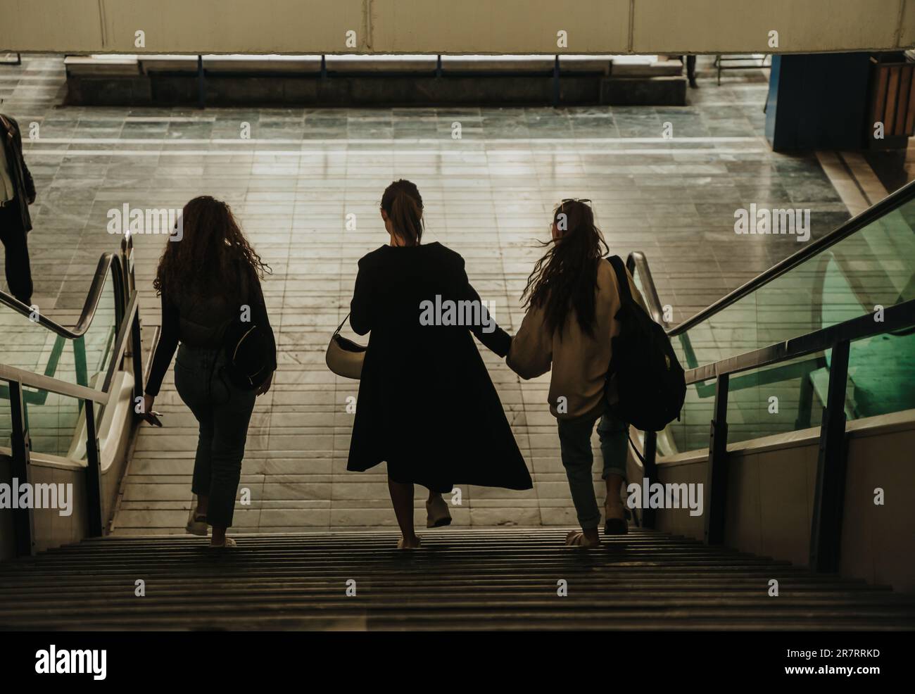 Back view shot of three girls walking downstairs at the shopping mall ...