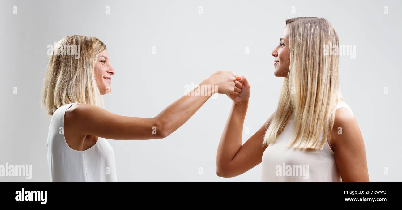 Two happy blondes engage in a special handshake, symbolizing their ...