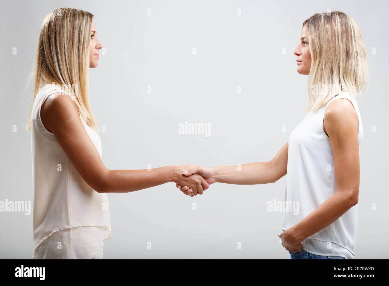 Two blondes in a business handshake, illustrating the power of educated ...