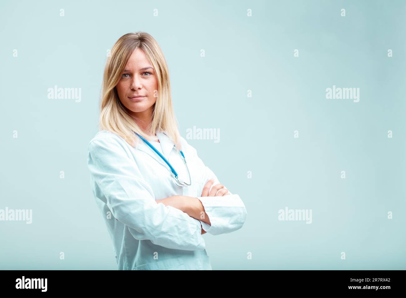 A professional and serious blonde doctor in a white coat stands with ...
