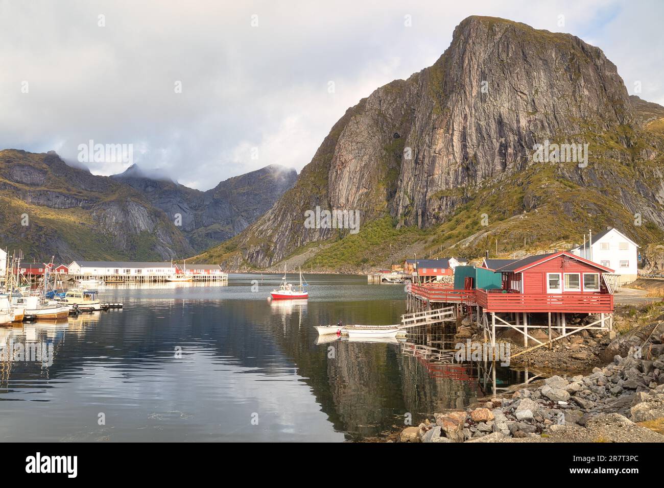 Red rorbuer on a stony shore, fishing boats, high, rugged mountains ...