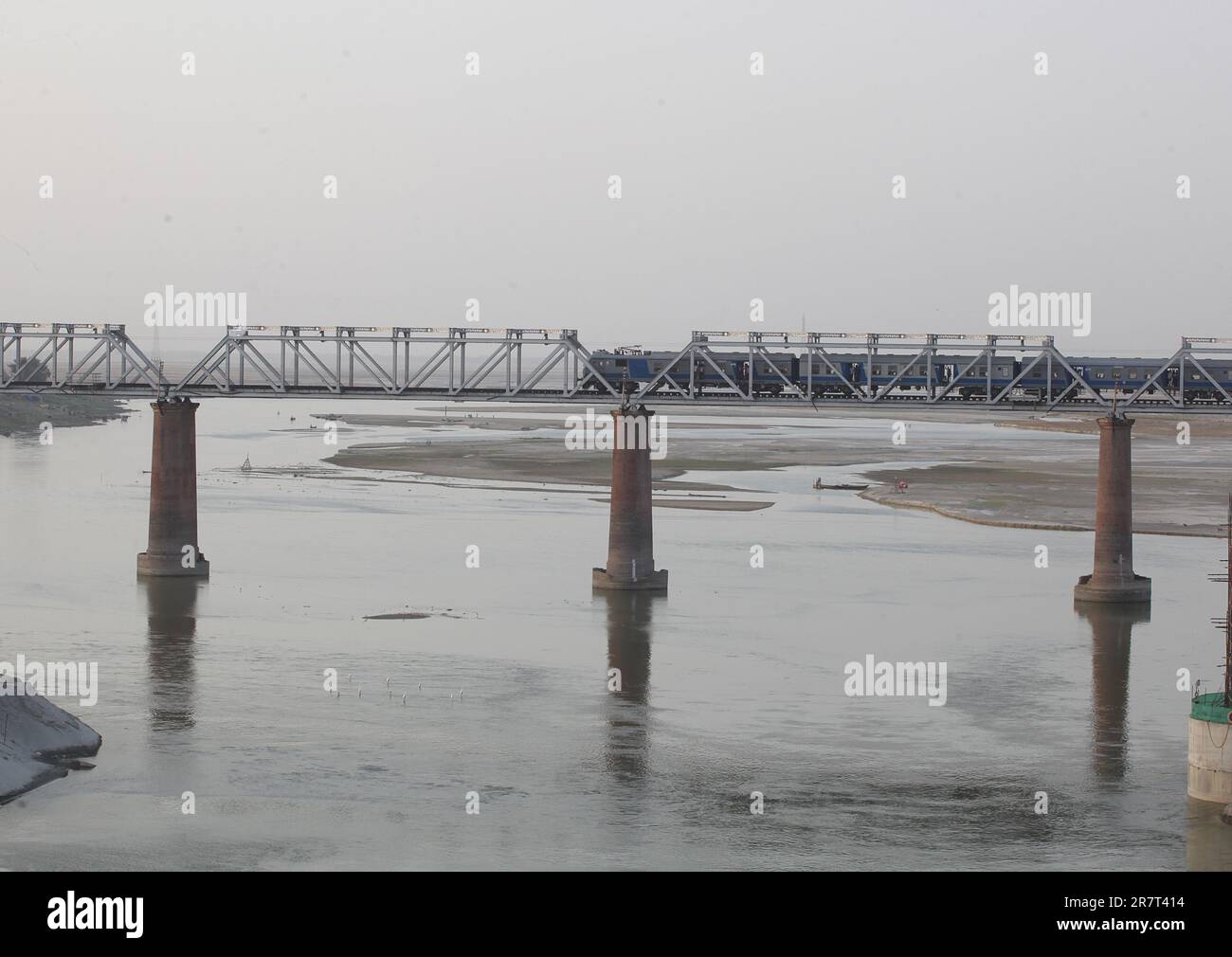 An Indian passenger train passes over a bridge on river Ganges in ...
