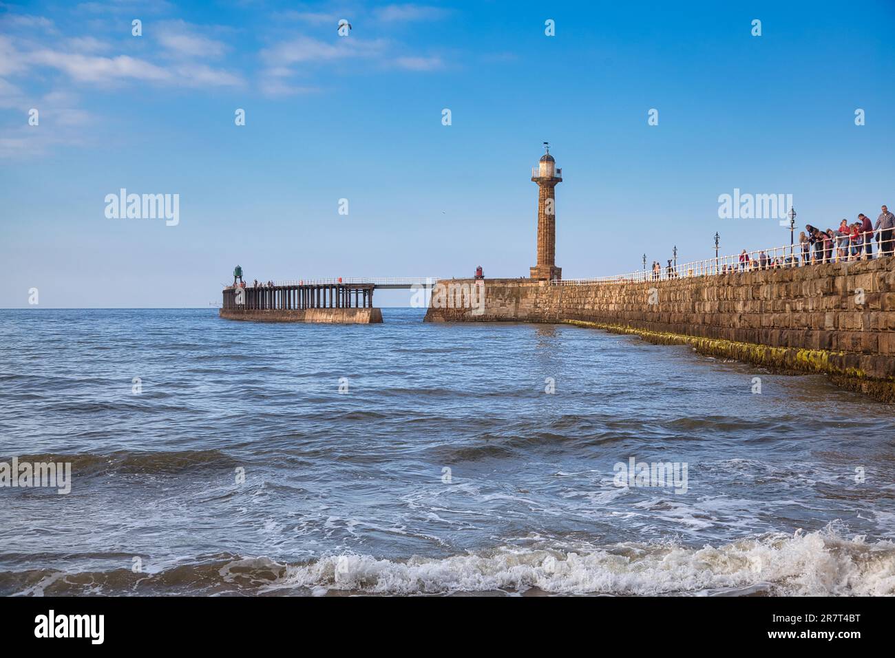 View of beach and pier with 19th century stone lighthouse, Whitby ...