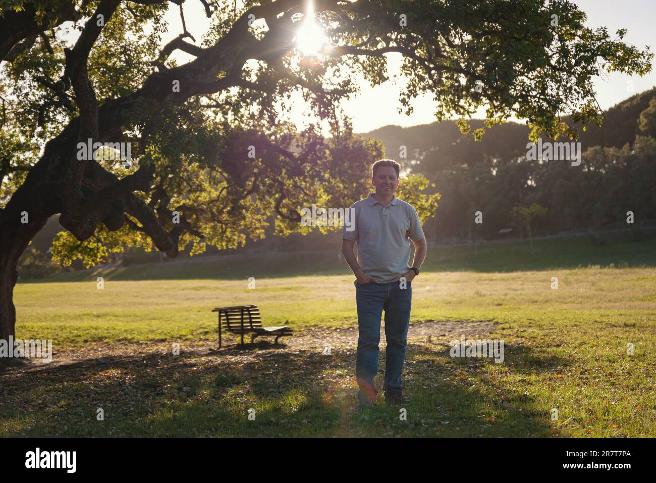 Smiling white man standing under big tree. Mid shot Stock Photo - Alamy