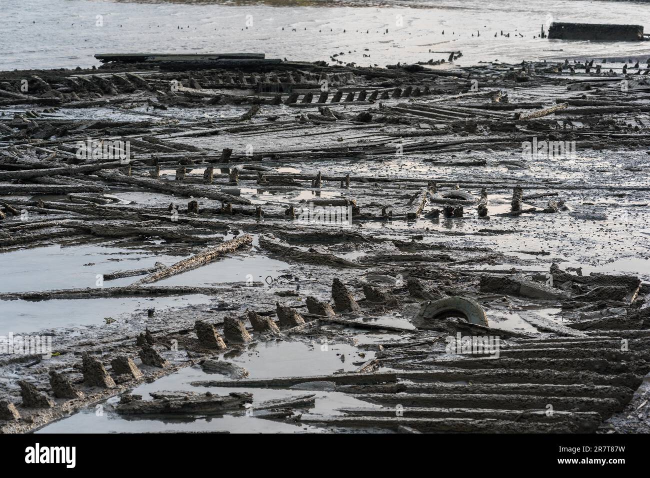 Parts of an old demolished jetty in the low tide in the mud of the ...